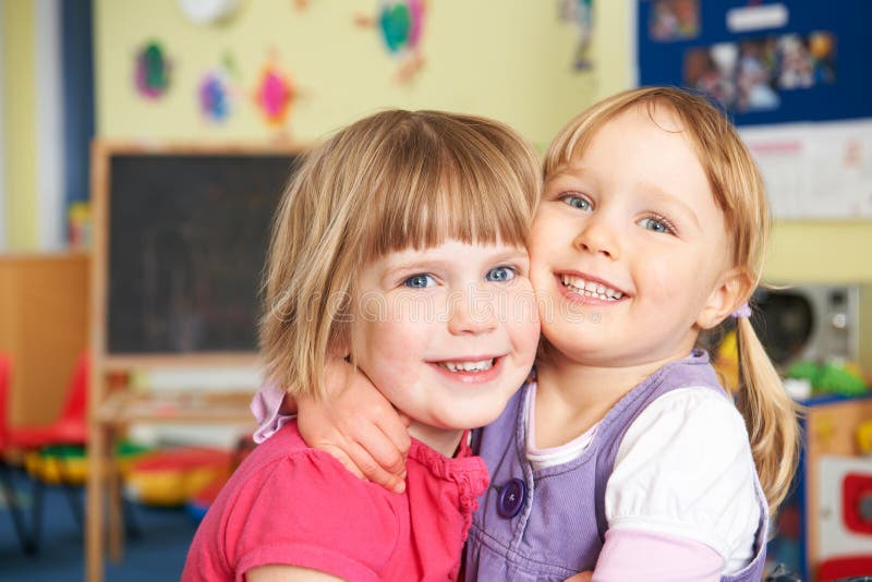 Two Female Pre School Pupils Hugging One Another. - Stock Image ...