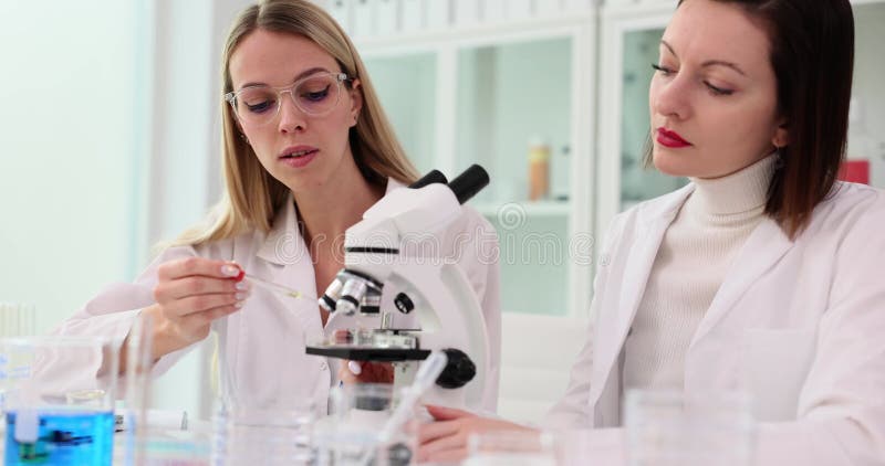 Two Female Scientists Working in a Lab Intern Dripping Liquid Onto the ...