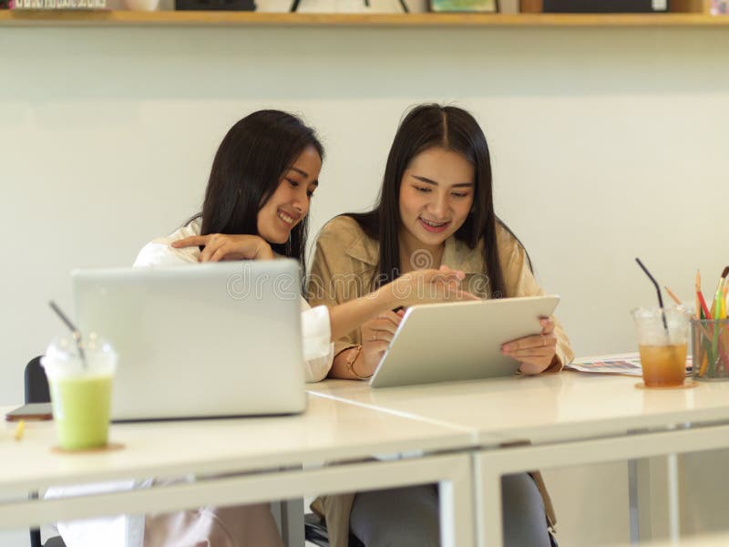 Two Female Students Having Funny Conversation while Doing Assignment in ...