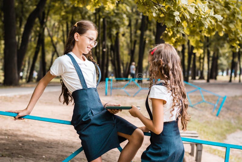 Two Female Students in School Uniforms Share a Book in the Park on a ...