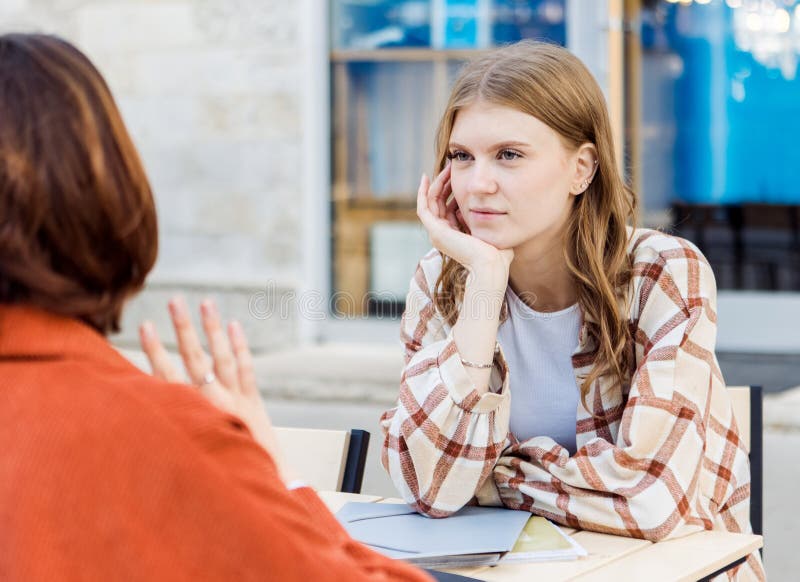 Two Female Students are Sitting at a Table Outside and Discussing Their ...
