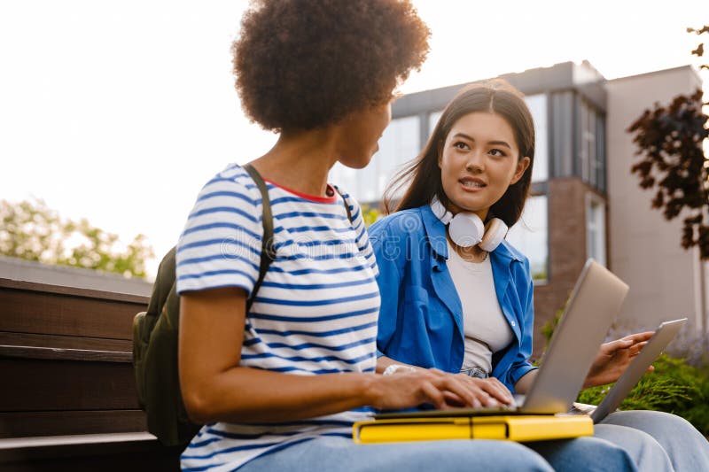 Two Female Students Studying and Using Laptops while Sitting in Campus ...