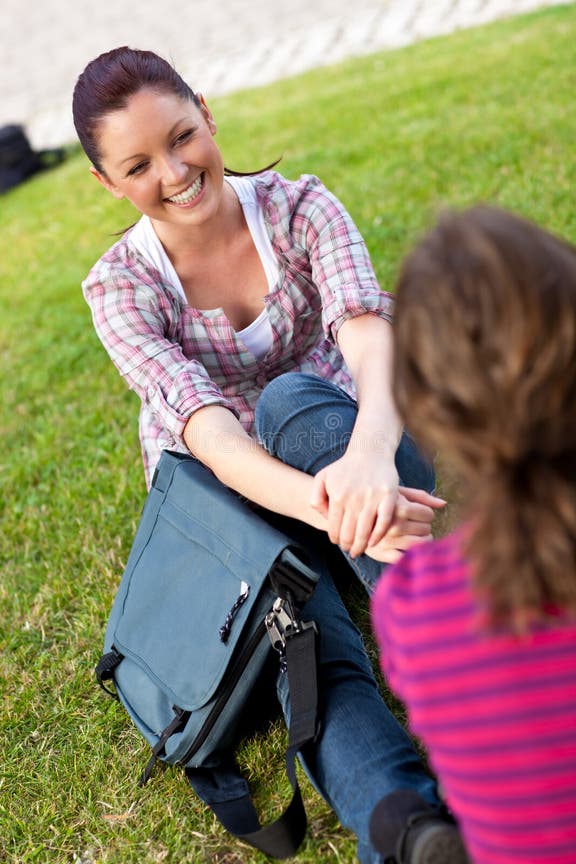 Two Female Students Talking Together Stock Photo - Image of lying, park ...
