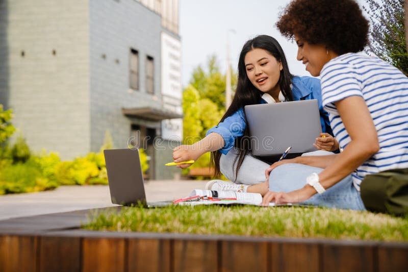 Two Female Students Using Laptops while Studying Together Outdoors in ...