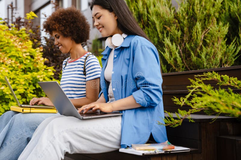 Two Female Students Working on Laptops while Sitting in Campus Stock ...