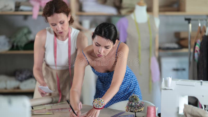 Two Female Tailors Work Together in a Sewing Workshop and Draw on Paper ...