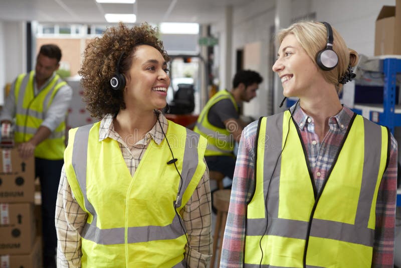Two Female Workers Using Headsets in Distribution Warehouse Stock Photo ...