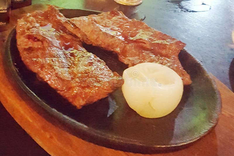 Two Fillets with Roasted Onions on a Wooden Plate Stock Photo - Image ...