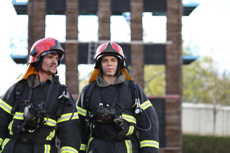Two Firefighters in Equipment and Red Helmets on Stock Image - Image of ...