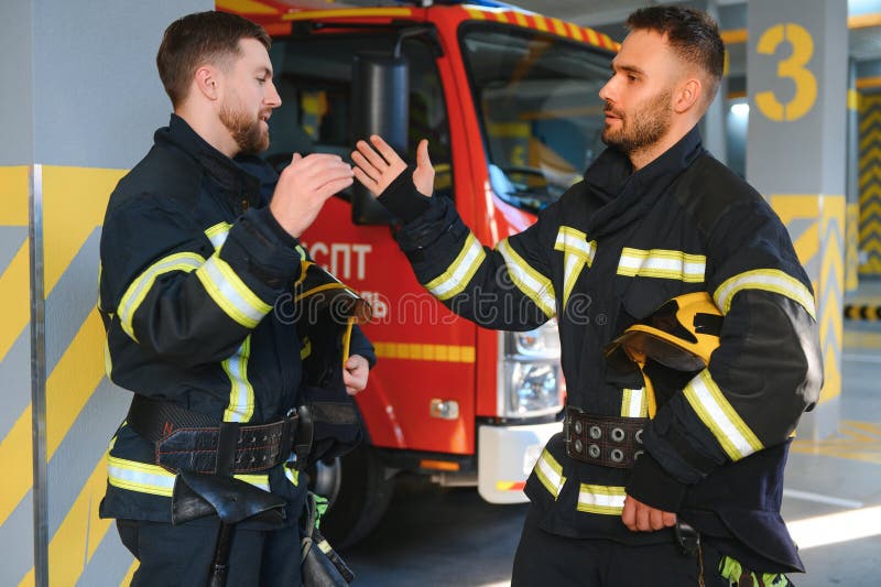 Two Firefighters in Protective Clothing in Helmets with Fire Engine ...