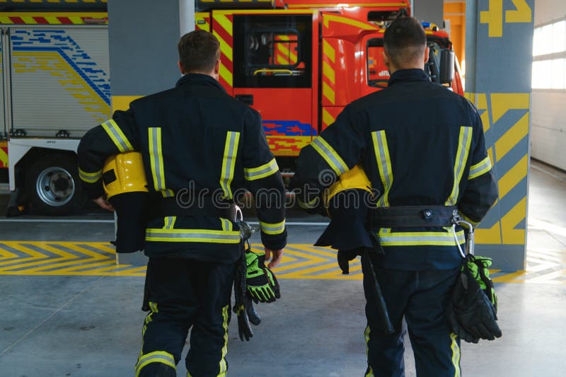 Two Firefighters in Protective Clothing in Helmets with Fire Engine ...