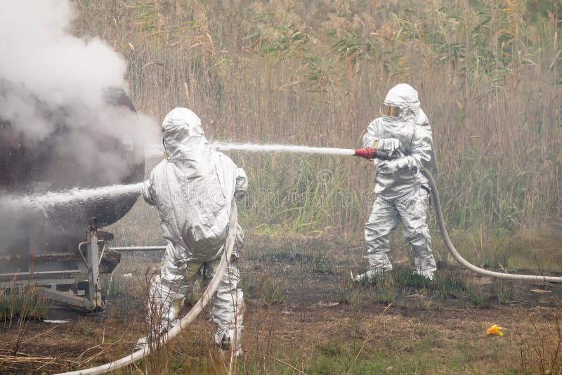 Two Firefighters in Protective Suits Works with Water Hose. Fighting ...