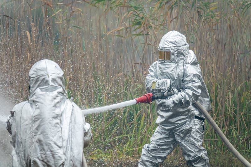 Two Firefighters in Protective Suits Works with Water Hose. Fighting ...