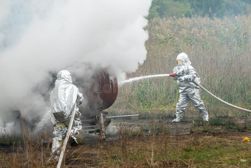 Two Firefighters in Protective Suits Works with Water Hose. Fighting ...