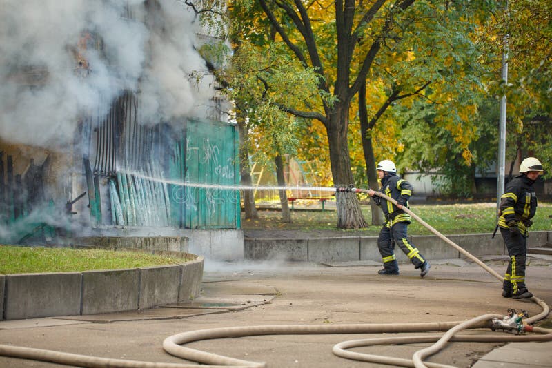 Two Firemen with Protective Uniform and Helmet Off the Fire Extinguish ...