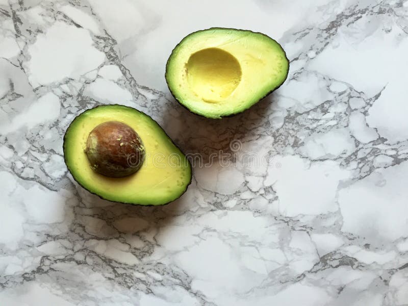 Two Fresh Avocado Halves with Pit on Marble Kitchen Countertop Stock ...