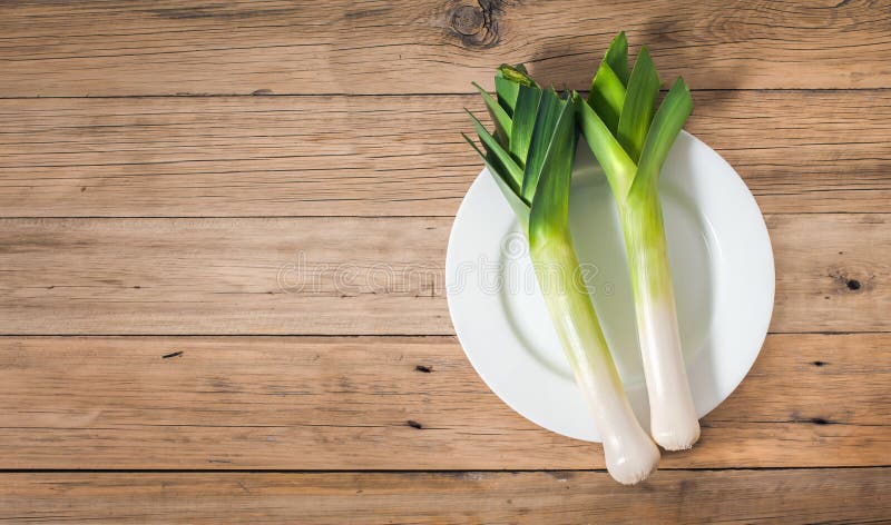 Two Fresh Raw Leeks Lie on a White Plate on an Old Wooden Table. View ...