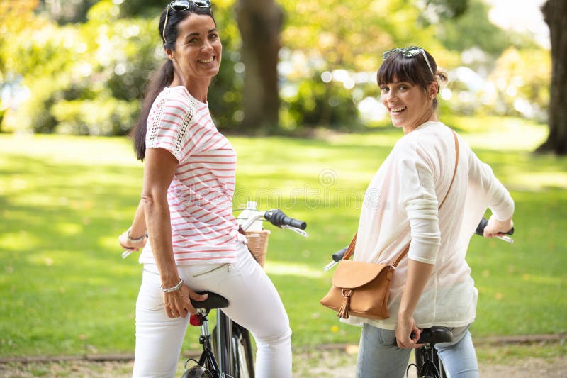 Two Friends on Bikes Looking Back Smiling Stock Image - Image of phone ...