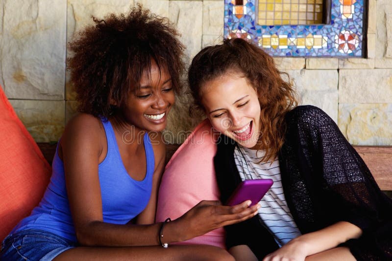 Two Friends Laughing and Looking at Mobile Phone Stock Photo - Image of ...