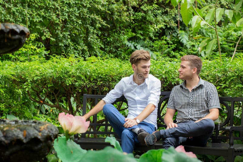 Two Friends Men Talking Sitting in a Garden. Stock Photo - Image of ...