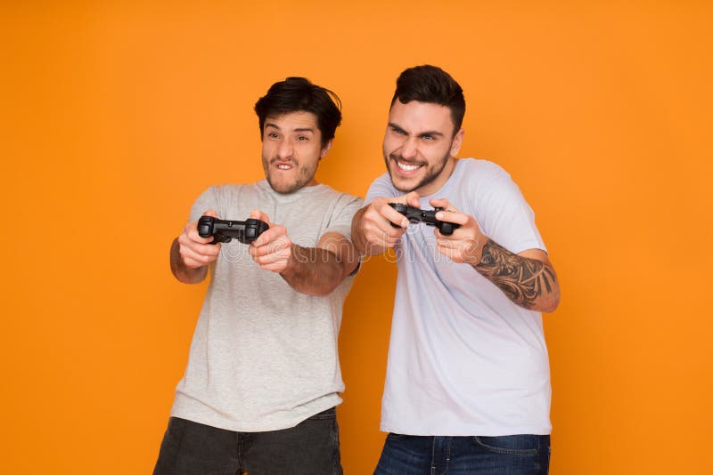 Two Friends Playing Video Games Over Orange Background Stock Photo ...