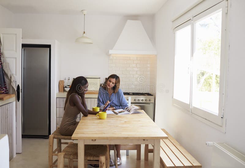 Two Friends Researching Recipies at the Kitchen Table, Full Length ...