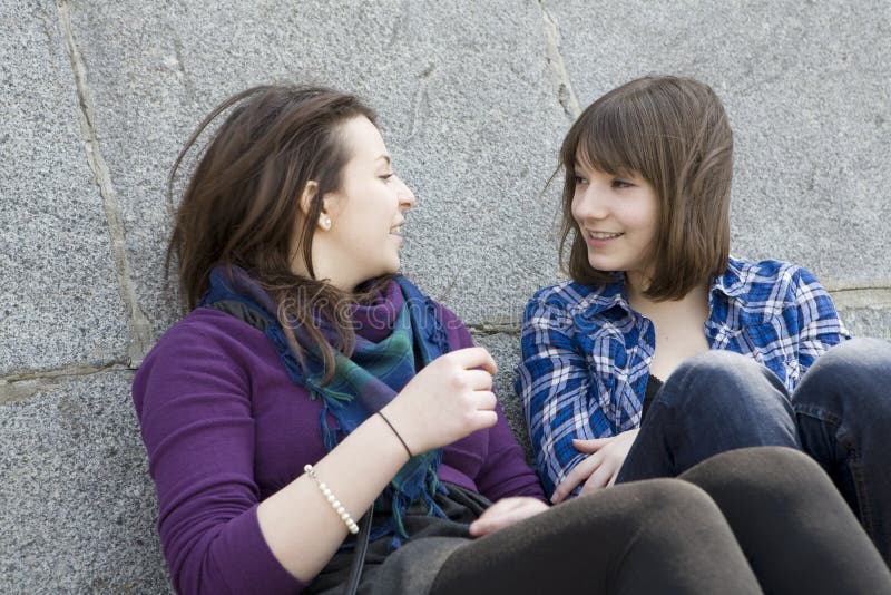 Two Friends Sitting Near Stone Wall. Stock Photo - Image of friend ...