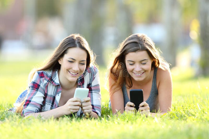 Two Friends Using Their Smart Phones on the Grass Stock Photo - Image ...
