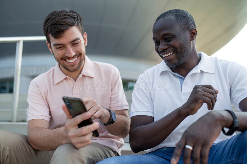 Two Friends Watching Something on the Phone and Smiling Stock Photo ...