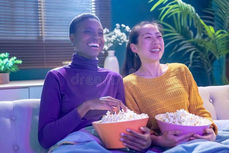 Two Girl Friends Sitting On Couch Watch A Movie And Eat Popcorn Funny Friends Relaxing Together