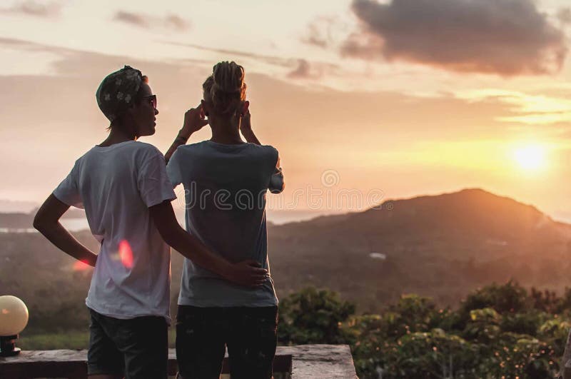 Two Girl Standing on a High, Hugging and Taking Picture of Sunset Stock ...