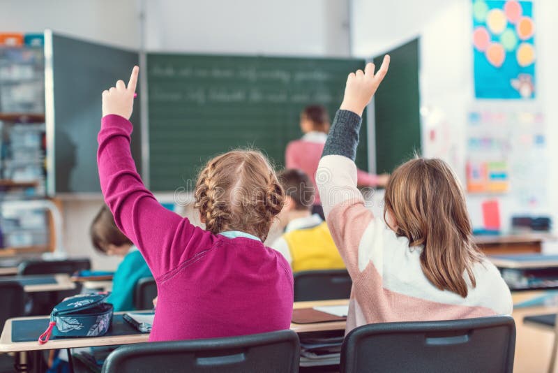 Two Girl Students Raising Hands To Answer a Question in School Class ...