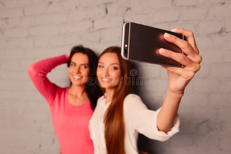 Two Girlfriends Make Selfie Photos On A Mobile Phone Stock Image