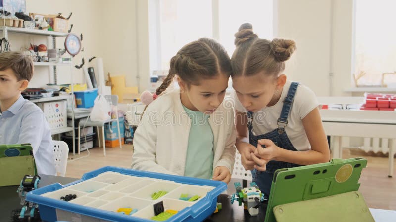 Two Girls Build the Plastic Robot Using the Instruction from Ipad at ...