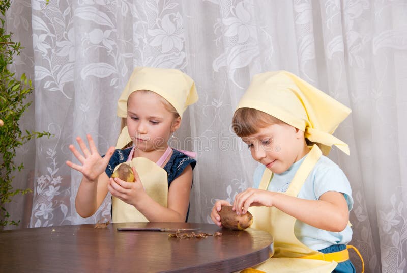 Two girls clean potatoes stock image. Image of siblings - 23987243