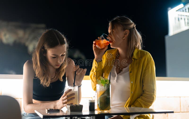 Two girls with cocktails stock image. Image of restaurant - 310806165