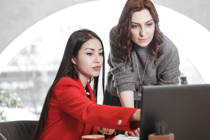 Two Girls Designers are Working with Laptop and Documentation at the ...