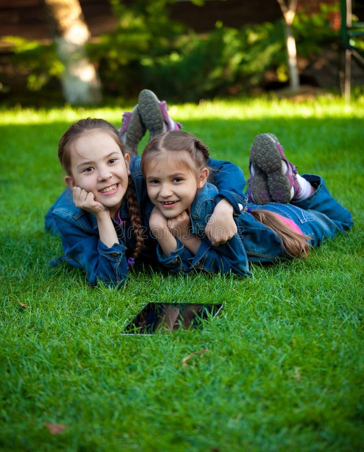 Two Girls Having Fun on Grass with Tablet Stock Image - Image of smile ...