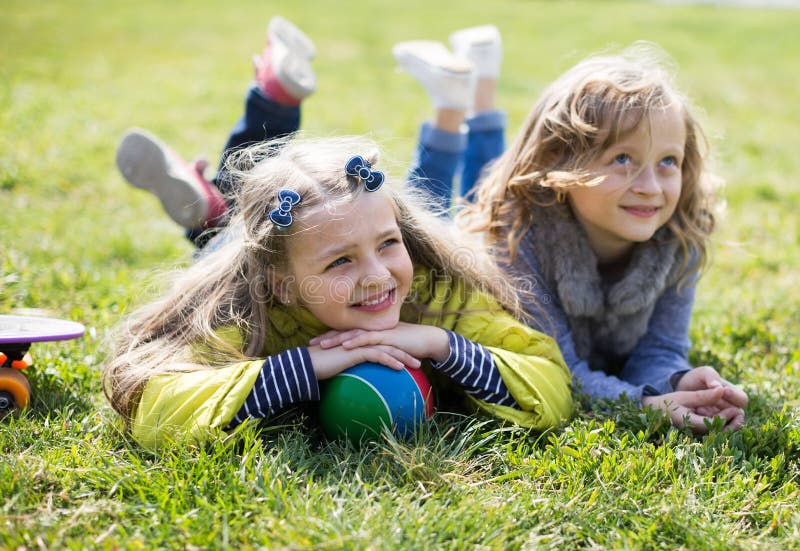 Two girls lie on grass stock photo. Image of park, friendship - 178990710