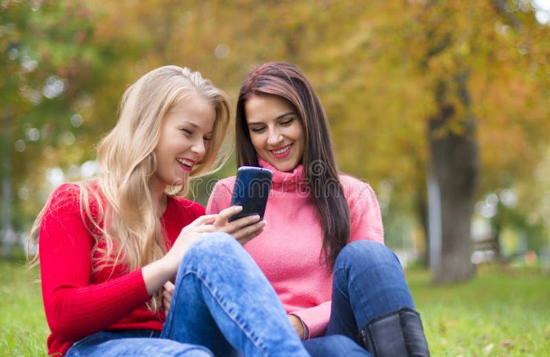 Two Girls in Park with a Mobile Phone in Autumn Stock Image - Image of ...