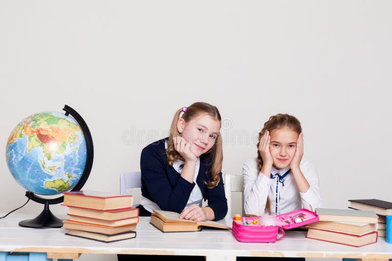 Two Girls of the School with Books for Studying Sit at the Desk in the ...