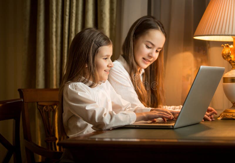 Two Girls Sitting at Table and Using Laptop Stock Photo - Image of ...