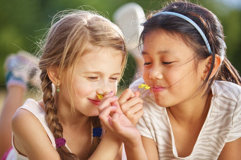 Two girls smell a flower stock photo. Image of friendship - 80636634