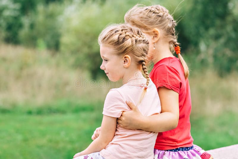 Two Girls Toddler Sisters Sit Hugging on the Bridge in the Park ...
