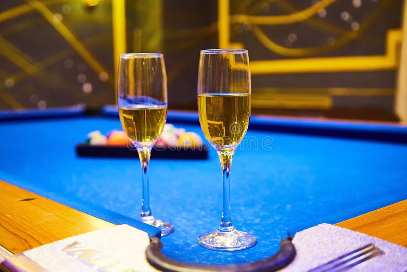 Two Glasses of Champagne Rest on a Blue Pool Table in a Dimly Lit Game ...