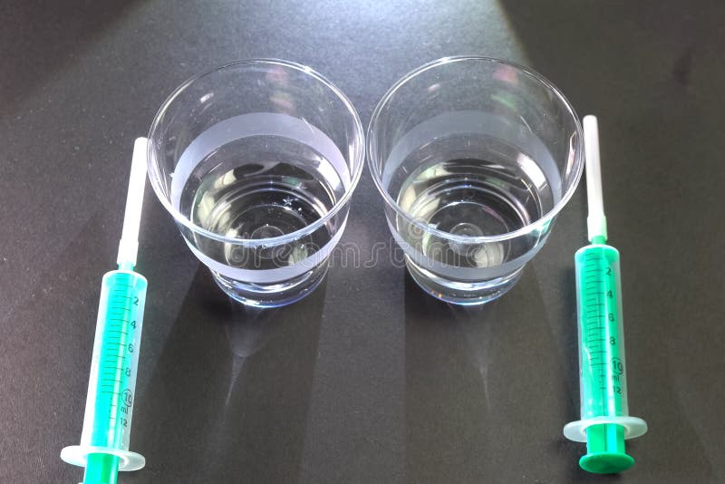 Two Glasses of Water and Two Syringes on Table Stock Photo - Image of ...