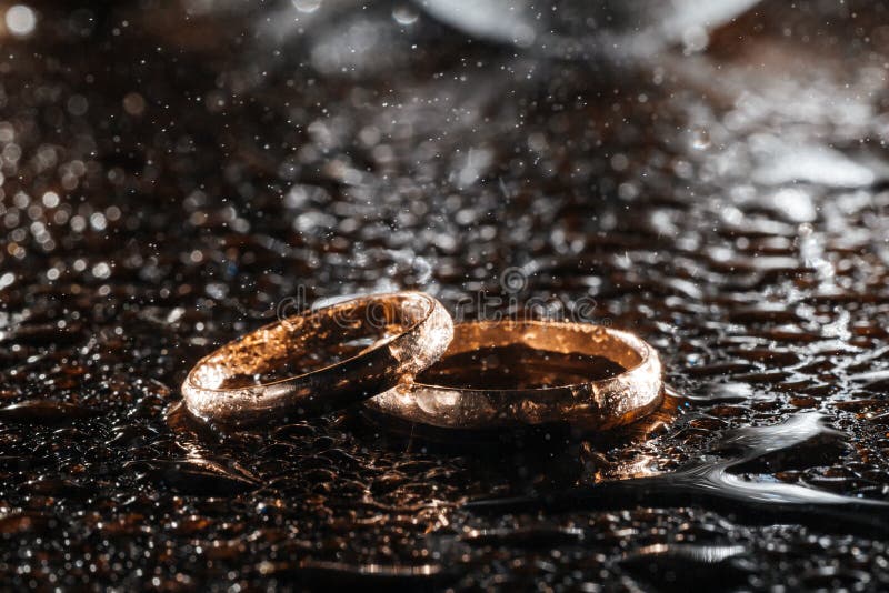 Two Gold Wedding Rings in Rain Drops on a Black Wet Background Stock ...