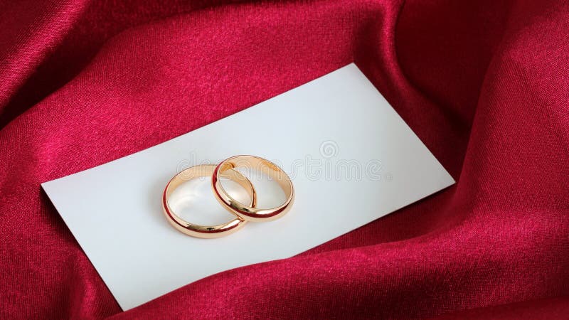 Two Golden Wedding Rings Resting on Blank White Card on Red Satin ...