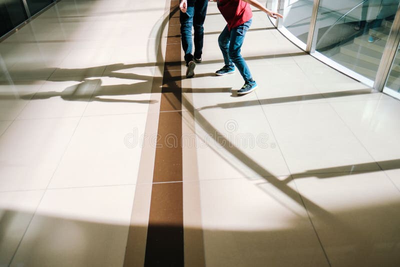 Two Guys Running in a Hallway of a Building in Front of the Windows on ...