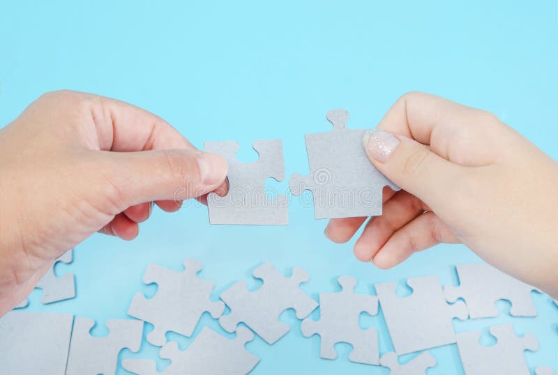 Two Hands Connecting a Puzzle on Blue. Close-up. Stock Photo - Image of ...